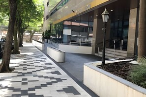 Um edifício moderno com fachada de vidro, um passeio com padrão e áreas de estar ao ar livre.