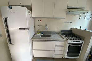 Uma cozinha compacta com geladeira, fogão, forno e um pequeno balcão.