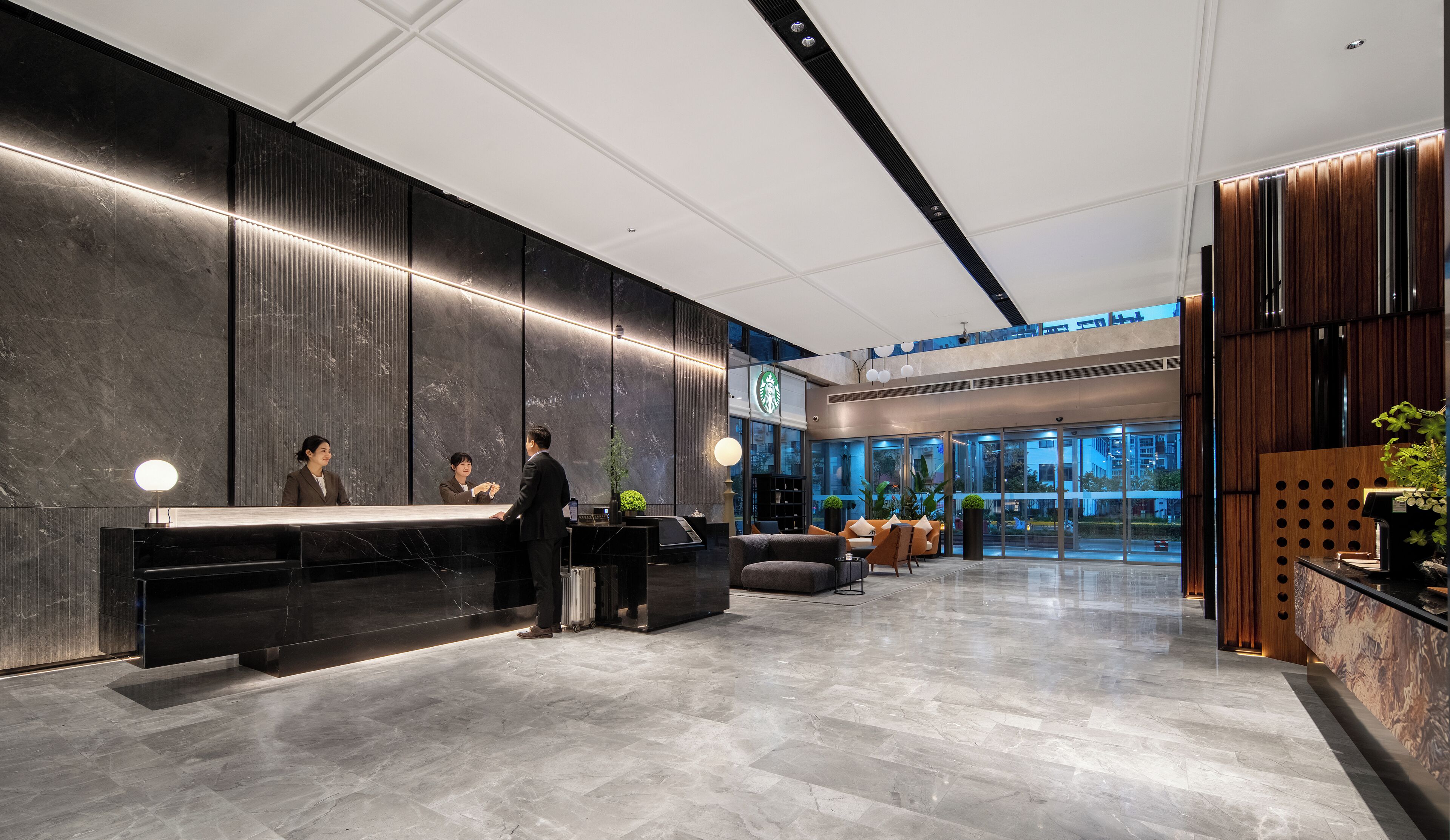 Um lobby de hotel moderno com balcão de recepção, área de estar e grandes janelas.