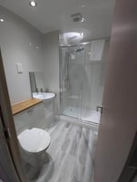 Uma casa de banho moderna com sanita, lavatório e cabine de duche de vidro.