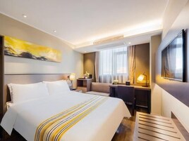 Quarto de hotel com uma cama grande, uma escrivaninha, uma cadeira e uma janela.