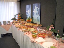 Mesa de buffet com diversos alimentos e uma garrafa de vinho.