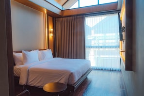 Quarto de hotel com cama, mesa de cabeceira, janela com cortinas e vista para o exterior.