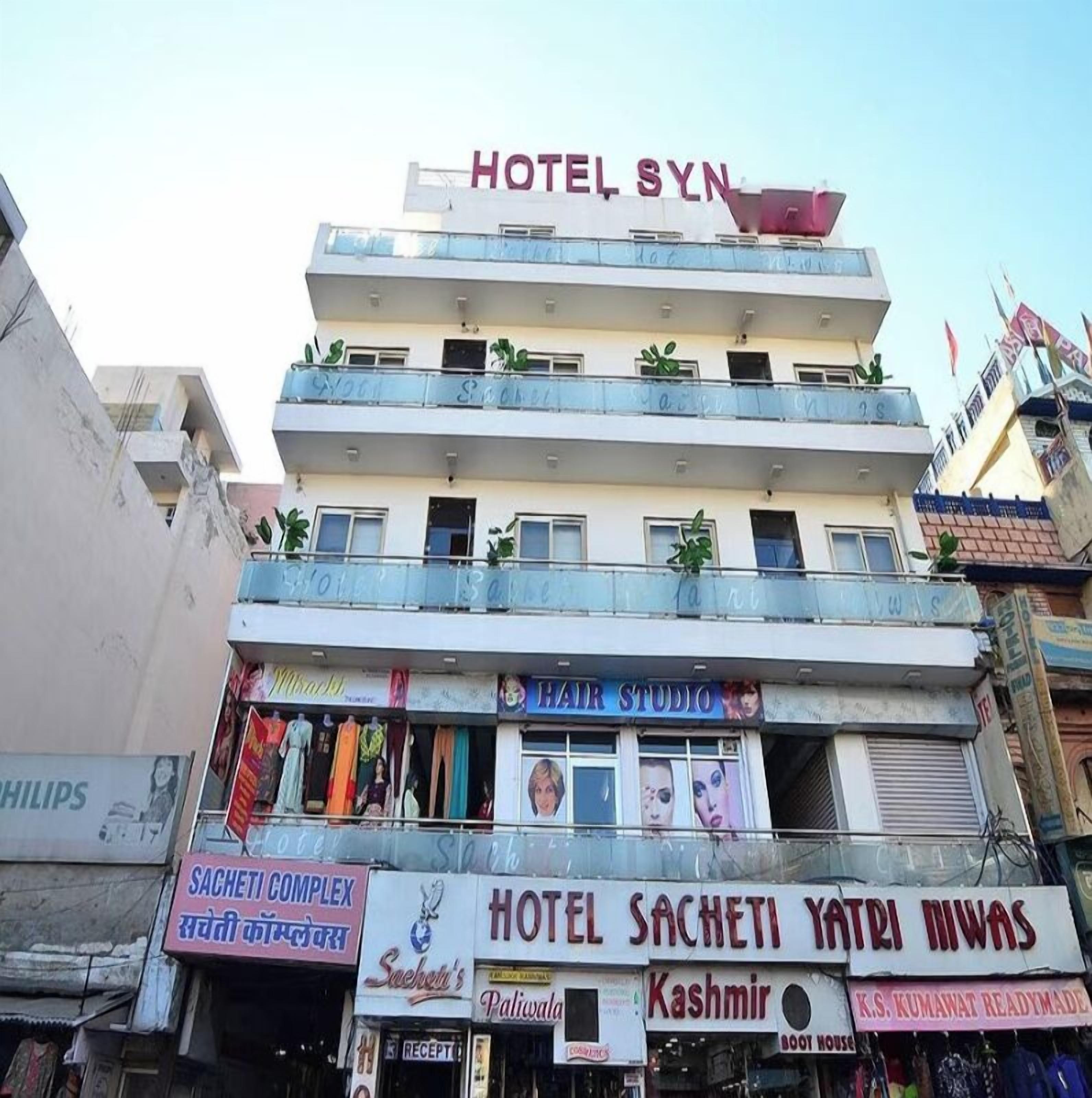 Um edifício de vários andares com uma placa indicando 'HOTEL SYN' no topo.