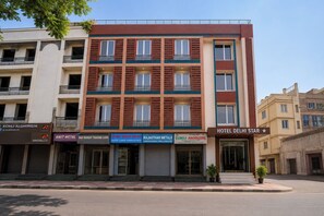 Um edifício com vários andares, com espaços comerciais no andar térreo e um hotel à direita.