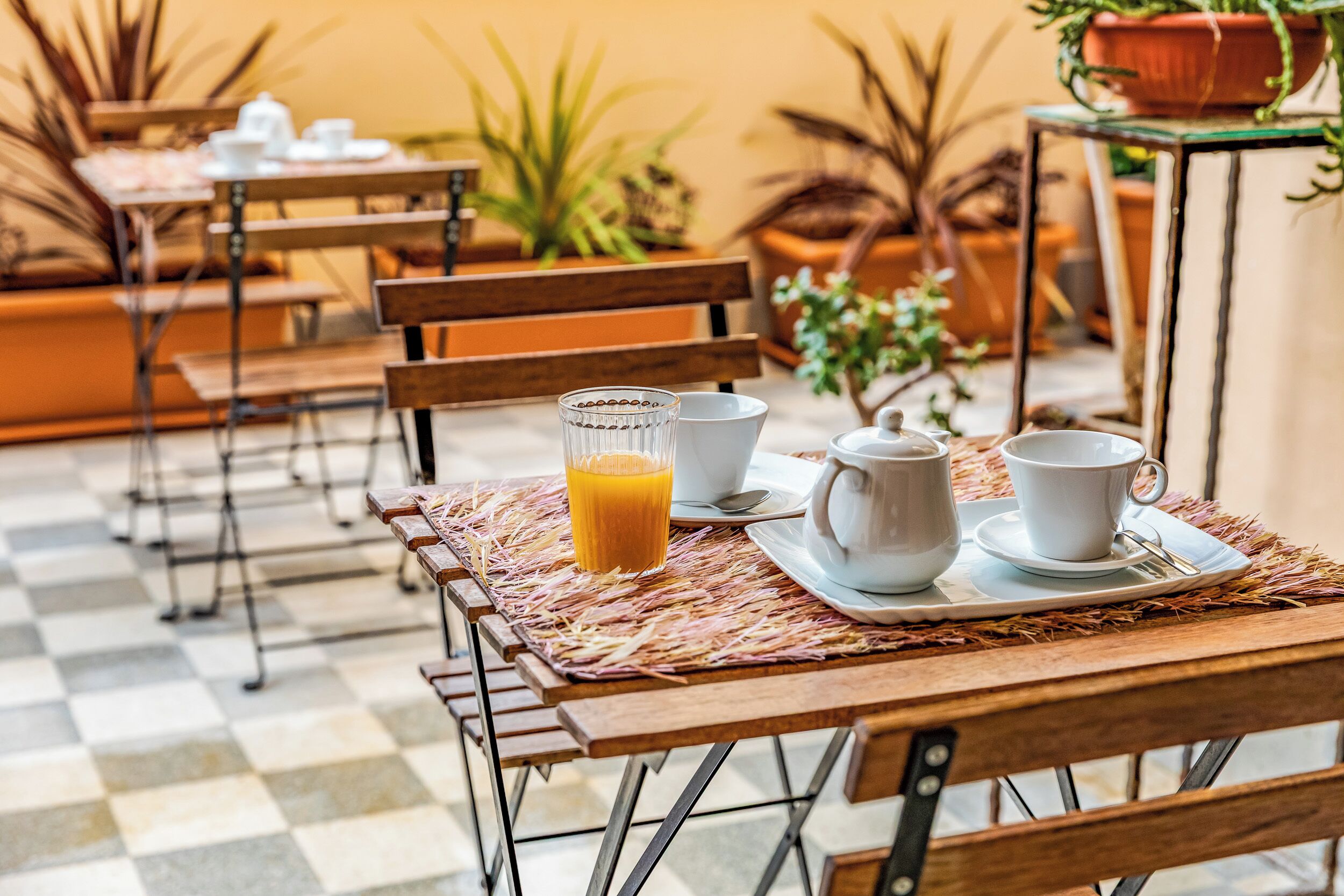 Um café com mesas, cadeiras e chão xadrez.