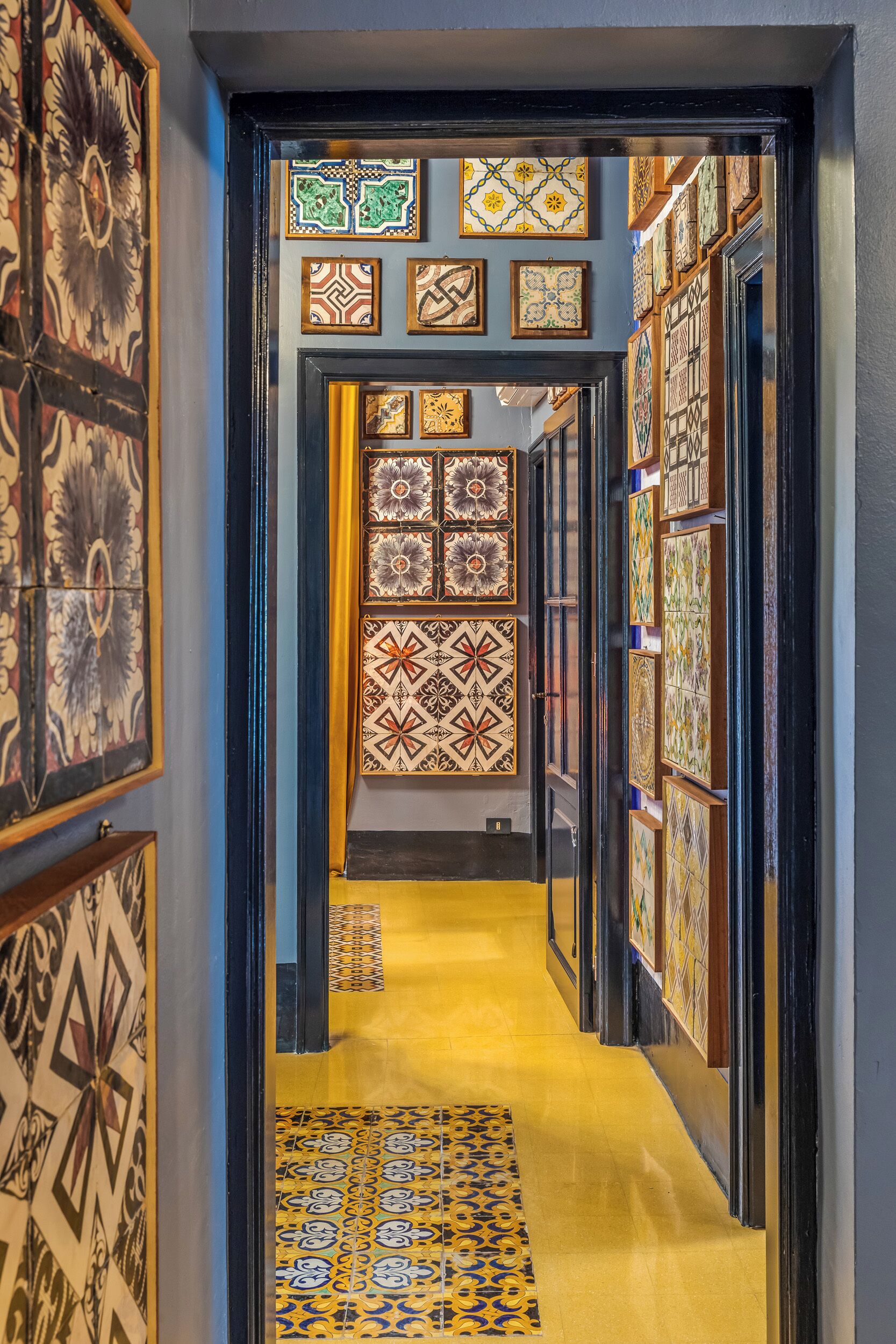 Um corredor com azulejos estampados nas paredes e no chão, que leva a uma porta.
