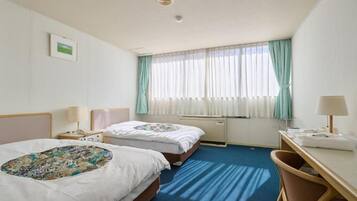 Quarto de hotel com duas camas, uma escrivaninha, uma cadeira, uma janela com cortinas e um pequeno quadro na parede.