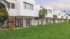 Um edifício residencial moderno com telhado plano, amplas janelas e um gramado bem cuidado.