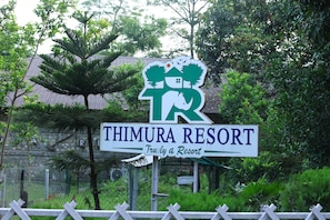 Placa do Thimura Resort com um logotipo que apresenta uma árvore e um rinoceronte.