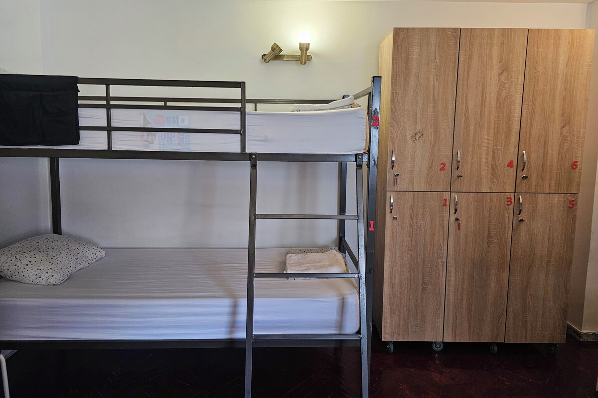 Uma cama de solteiro com travesseiro e um guarda-roupa com compartimentos numerados.