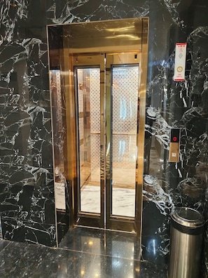 Um elevador com porta de vidro e um interruptor de alarme de incêndio na parede.