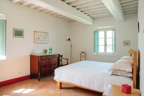 Quarto com cama, penteadeira, luminária, janela e obras de arte.