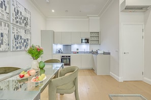 Uma cozinha moderna com armários brancos, uma mesa de jantar com cadeiras e um vaso com flores.