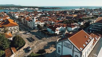 Uma vila costeira com edifícios históricos, uma praça central e vista para o mar.