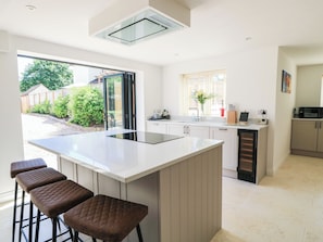 Uma cozinha moderna com uma ilha grande, banquetas e vista para o jardim.