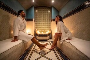 Um spa com duas pessoas sentadas em bancos, uma parede estampada e um chão de azulejos.