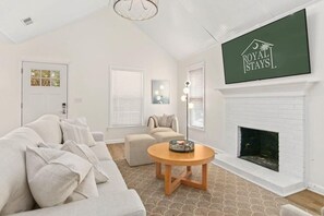 Uma sala de estar moderna com um sofá branco, uma mesa redonda de madeira e uma lareira.