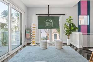 Quarto de hotel moderno com uma grande porta de vidro deslizante que dá para uma varanda, um letreiro verde com o logotipo 'ROYAL STAYS', um radiador branco e uma planta em vaso.