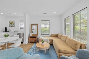 Uma sala de estar moderna com um sofá, uma mesa de centro e um espaço de jantar com uma mesa e cadeiras brancas.