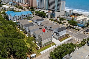 Vista aérea de uma área residencial com casas modernas, um porto de iates e uma praia.