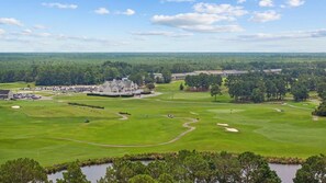 Um campo de golfe com um clube, vários edifícios e uma ampla área de estacionamento.