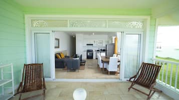 Uma sala de estar com sofá, cadeiras, uma mesa de jantar e uma cozinha ao fundo.