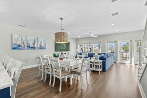 Ampla sala de estar com mesa e cadeiras para refeições, um sofá azul e um letreiro verde na parede.