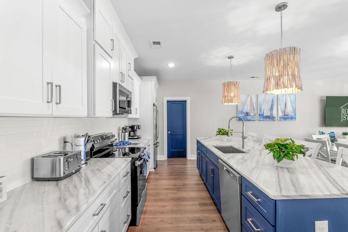 Cozinha moderna com armários brancos, bancada de mármore e uma parede azul como destaque.