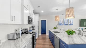 Cozinha moderna com armários brancos, bancada de mármore e uma parede azul como destaque.