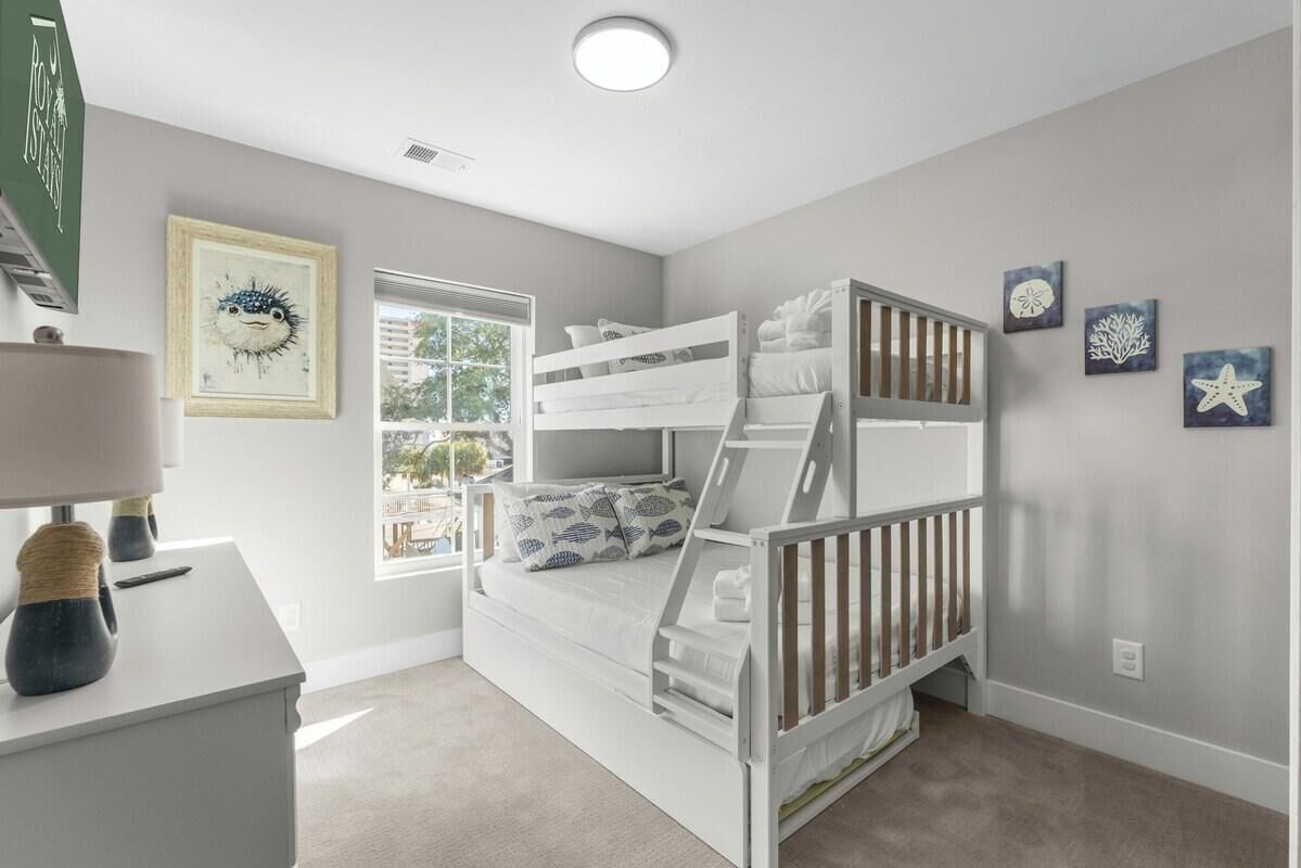 Quarto de criança com uma cama beliche, uma escrivaninha com abajur e uma janela com vista para o exterior.