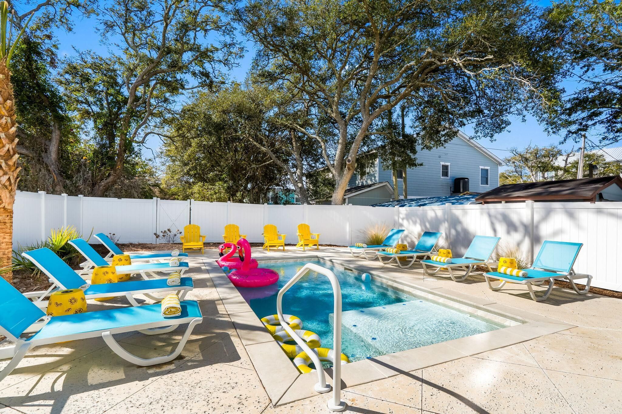 Uma área de piscina com espreguiçadeiras, um boi flamingo flutuante e um céu azul límpido.