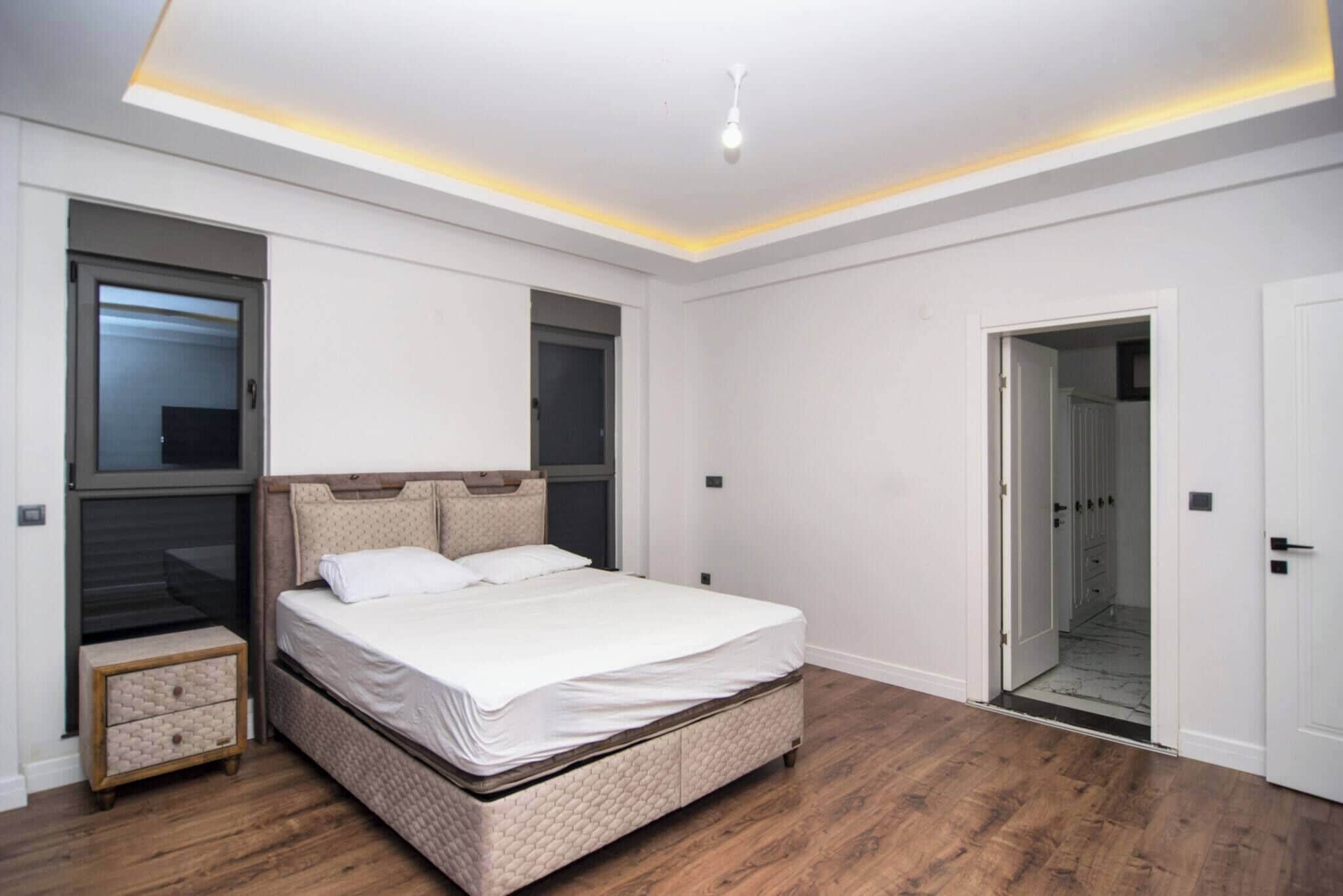 Quarto com cama, mesa de cabeceira, guarda-roupa e porta para um banheiro.