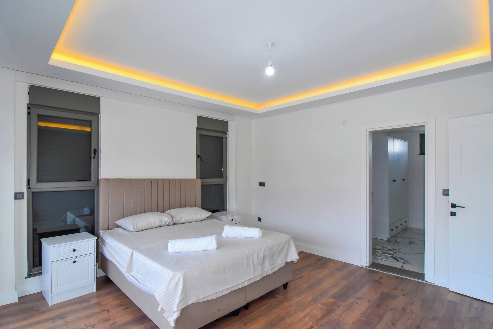 Quarto com cama, mesas de cabeceira e porta para um banheiro.