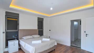 Quarto com cama, mesas de cabeceira e porta para um banheiro.