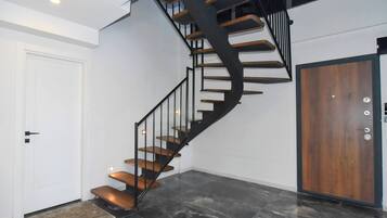 Um interior moderno com uma escada em espiral, uma porta branca e uma porta de madeira.
