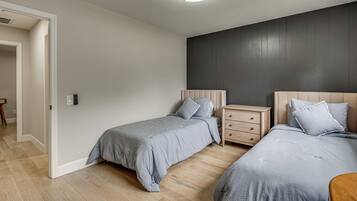 Quarto com duas camas, mesa de cabeceira, guarda-roupa e ventoinha no teto.