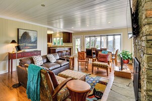 A spacious living area with a leather sofa, wooden chairs, a coffee table, and a stone fireplace.