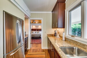 A kitchen with a stainless steel refrigerator, granite countertop, and a built-in sink.