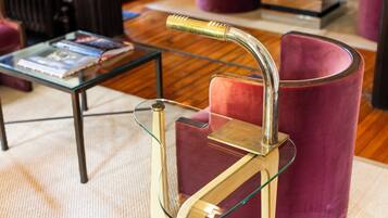 Um interior moderno com uma mesa de vidro, uma luminária de metal e uma cadeira estofada vermelha.