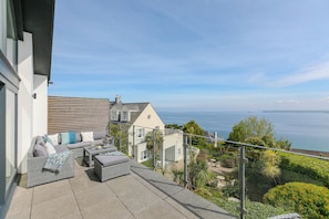 Varanda com mobiliário exterior, vista para o mar e edifícios vizinhos.