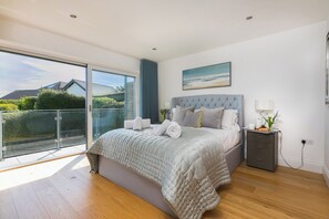 Quarto com uma cama grande, mesa de cabeceira, luminária e um quadro na parede.