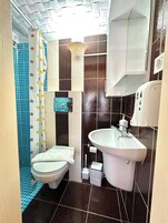 Casa de banho com sanita, lavatório e zona de duche.