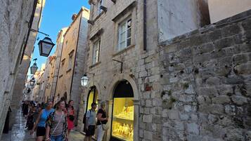 Uma rua estreita com edifícios de pedra, uma loja com vitrine e pedestres.