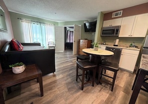 Um espaço compacto com cozinha compacta, área de refeições e quarto com cama e mesa de cabeceira.