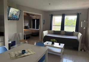 Um quarto acolhedor com uma cama, um sofá, uma mesa de jantar e uma televisão na parede.