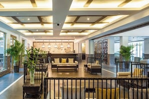 Um hall amplo com área de estar central, balcão de recepção e vista para o exterior.