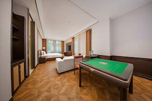 Quarto de hotel com mesa de bilhar, cama, sofá e televisão.