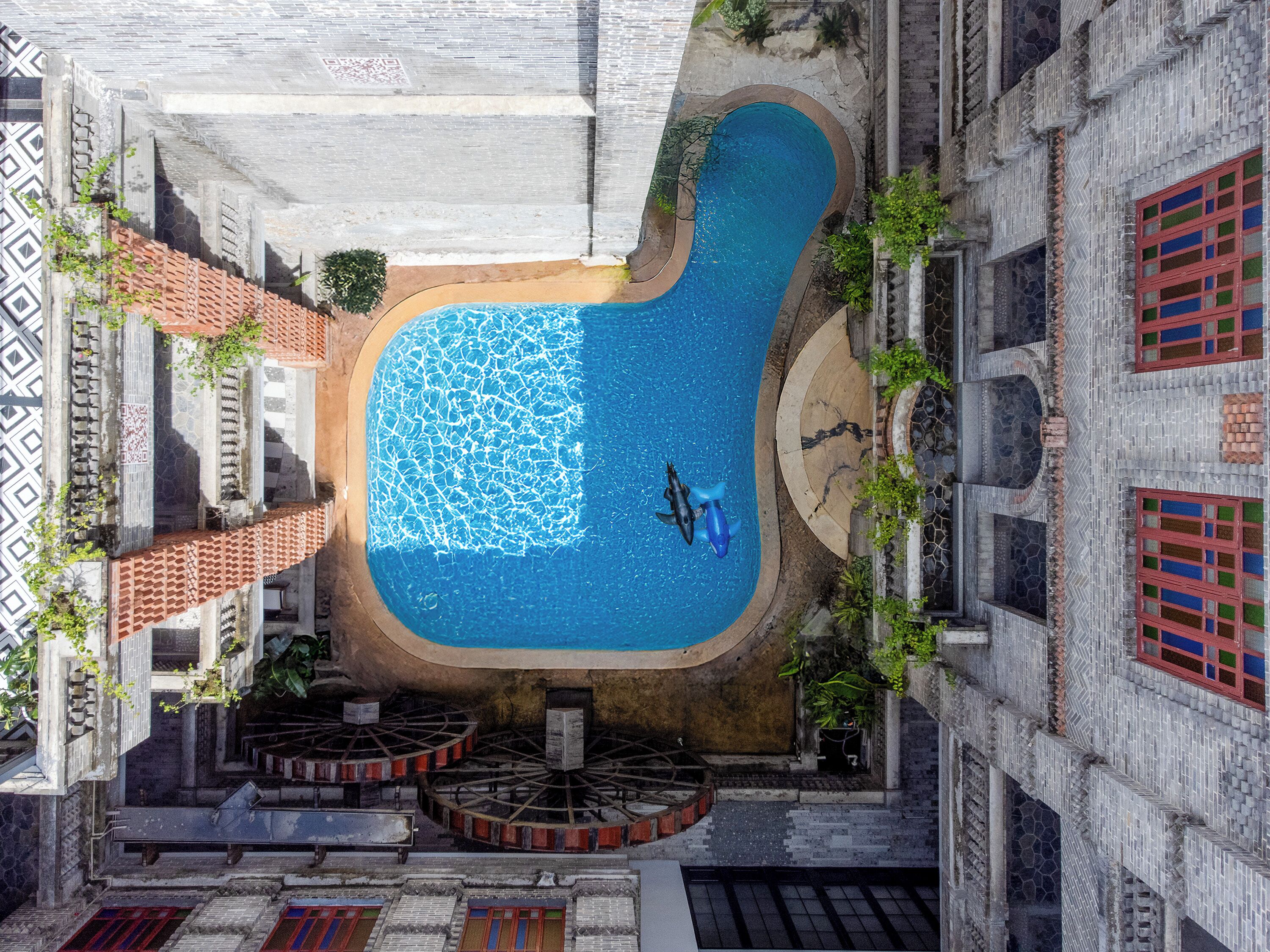 Vista aérea de uma piscina rodeada por edifícios com fachadas e janelas estampadas.