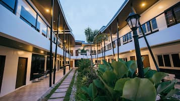 Um pátio de hotel com um caminho central, área de estar ao ar livre e várias varandas.